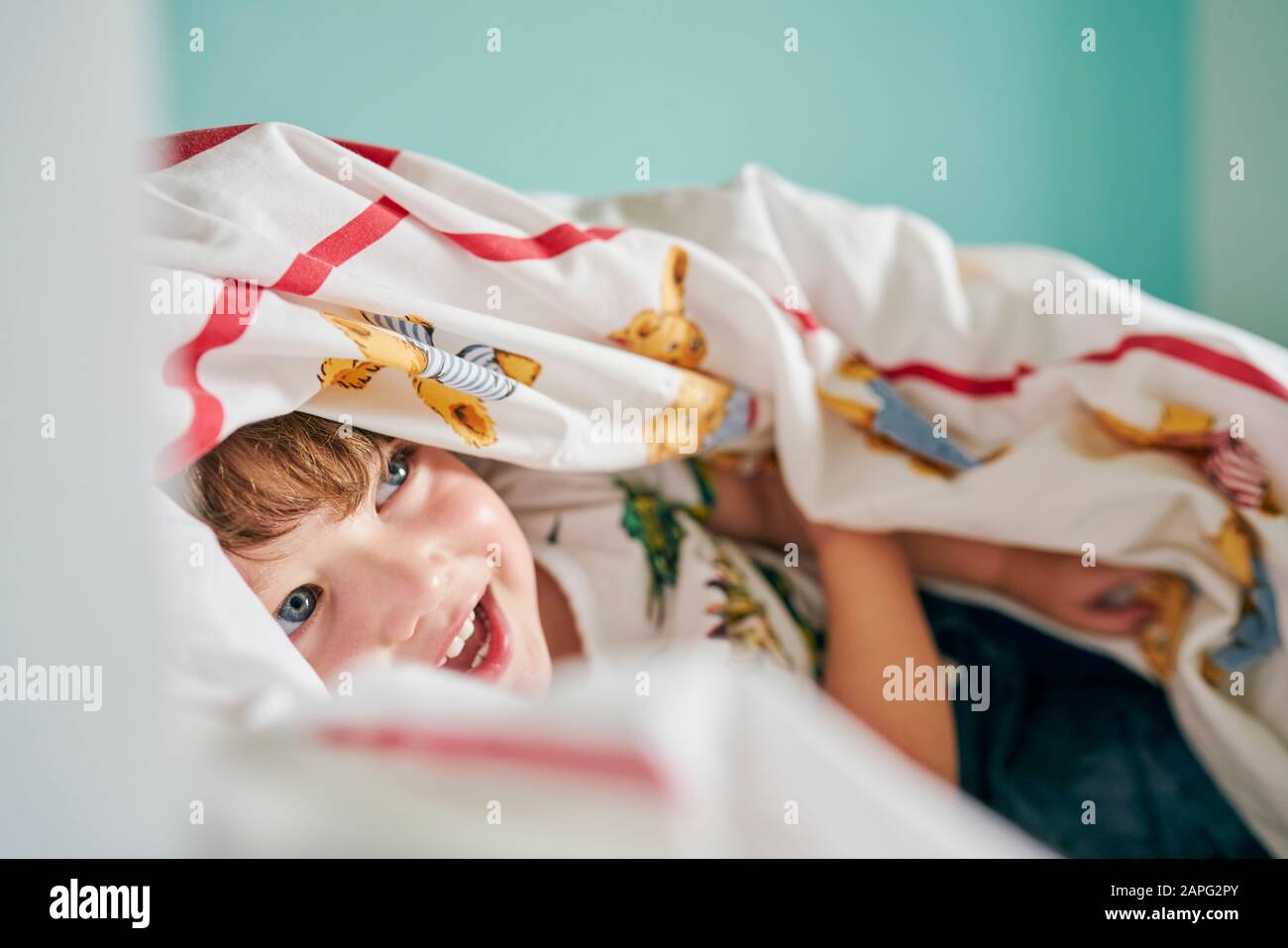 Toddler hiding under blanket in room Stock Photo - Alamy