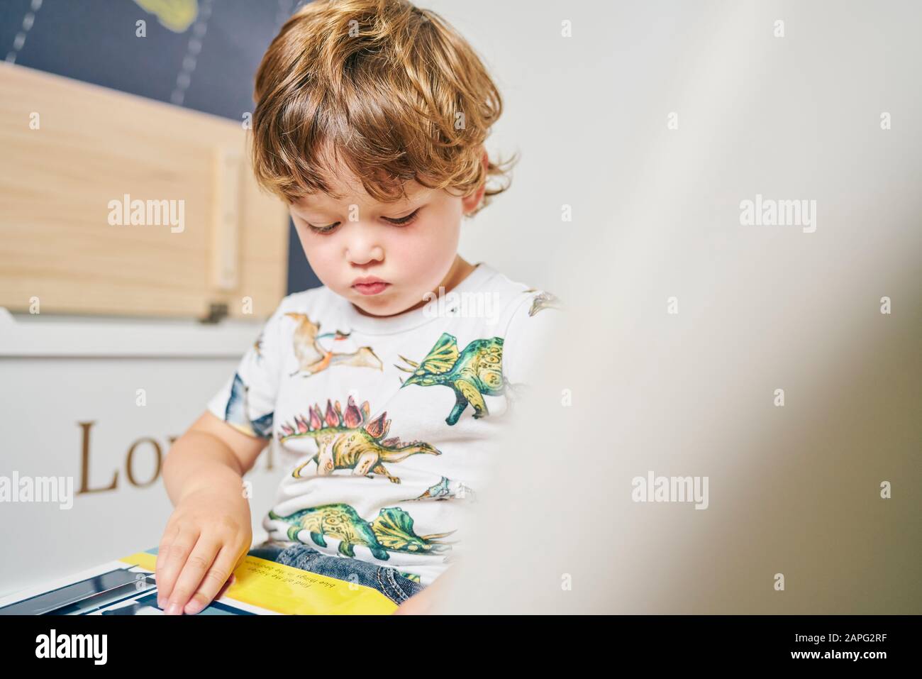 Toddler reading book in room Stock Photo - Alamy