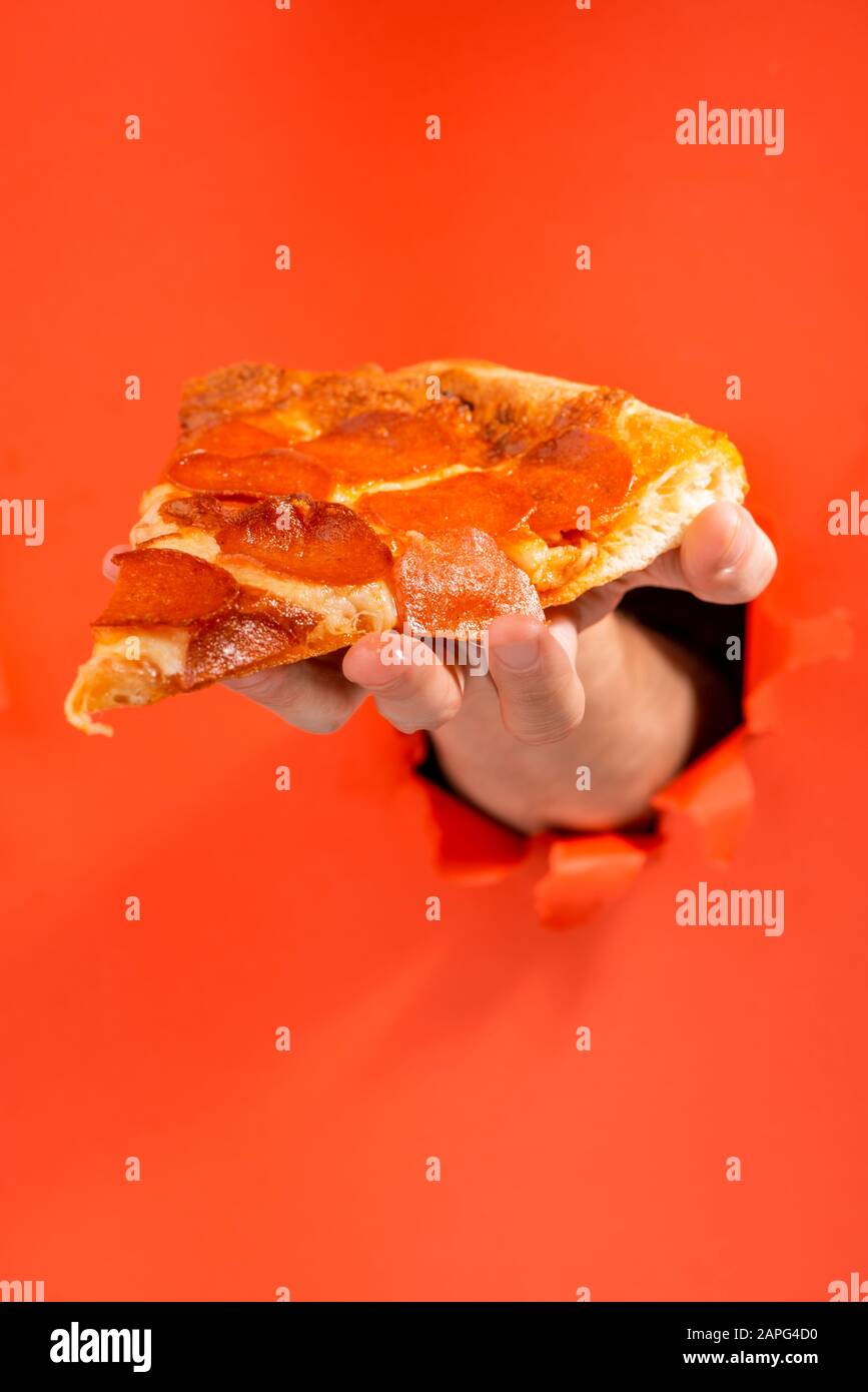 Hand giving a slice of Pepperoni pizza Stock Photo - Alamy