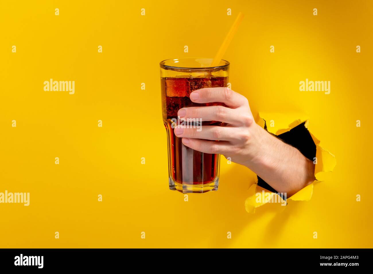 Hand holding a glass of cola with a straw Stock Photo - Alamy