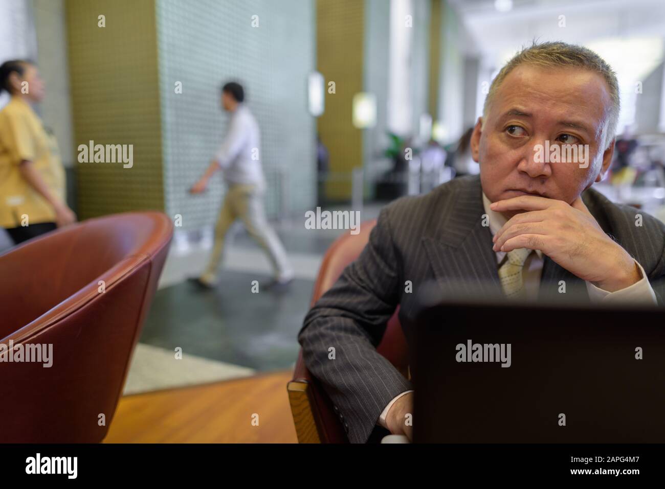 Portrait of mature Japanese businessman relaxing inside the coffee shop ...