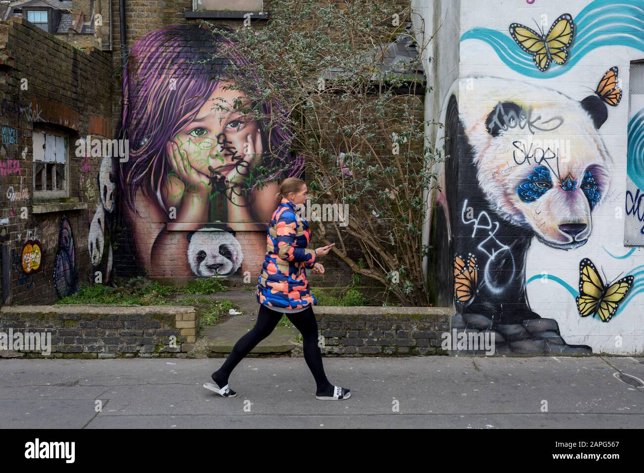 A lady walks past graffiti and urban artwork that features pandas and a ...