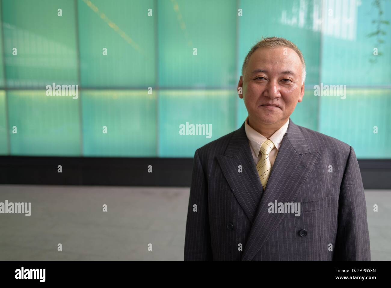 Portrait of mature Japanese businessman in suit exploring the city of ...