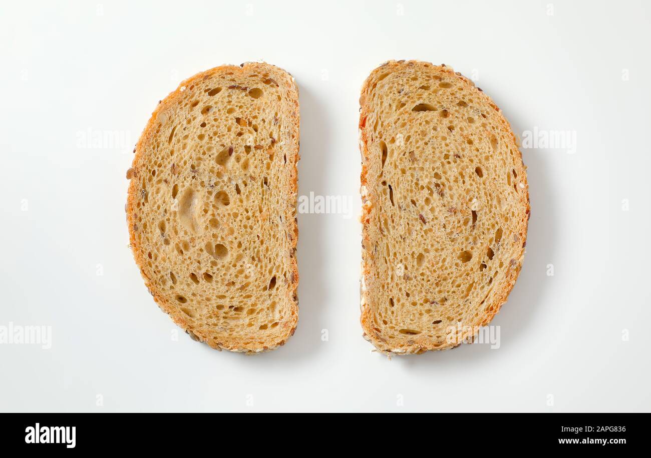 Two slices of whole grain bread, crust topped with rolled oats and ...