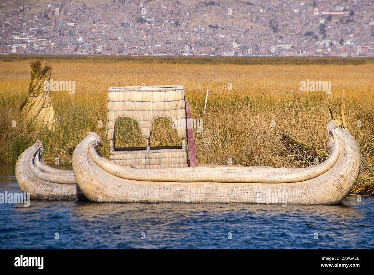 Wooden outriggers on the water by the grass covered field with a city ...