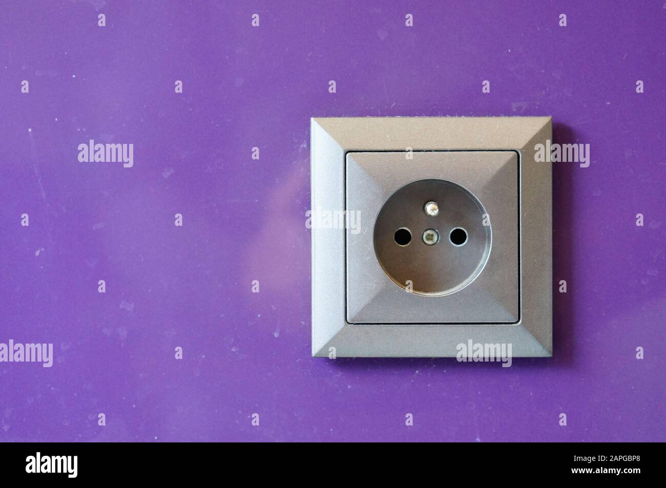 Electric outlet on a purple wall Stock Photo - Alamy