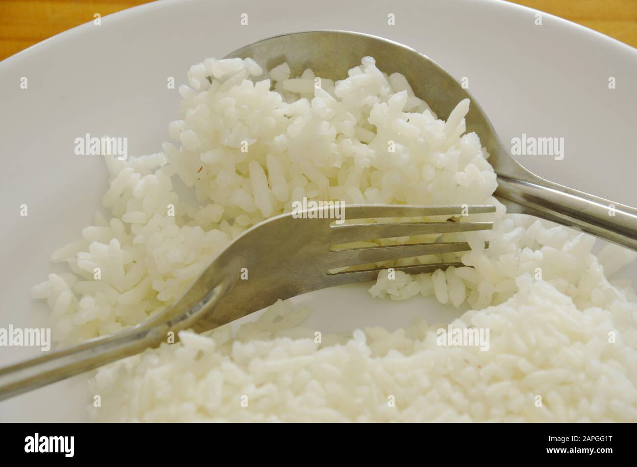 rice scooping by spoon and fork from plate for eating Stock Photo - Alamy