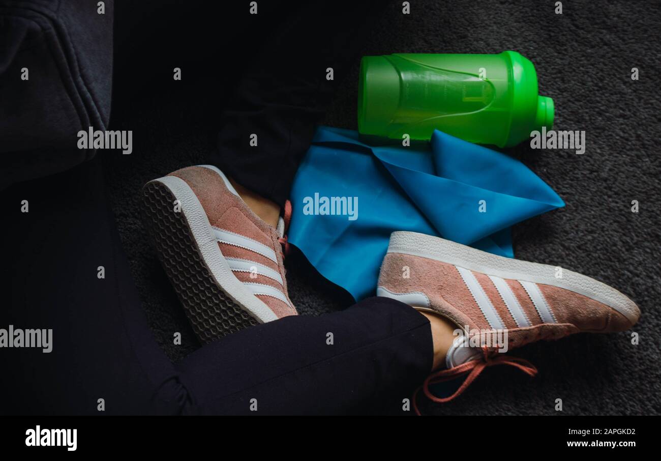 Overhead shot of a female sitting on the ground wearing sport shoes ...