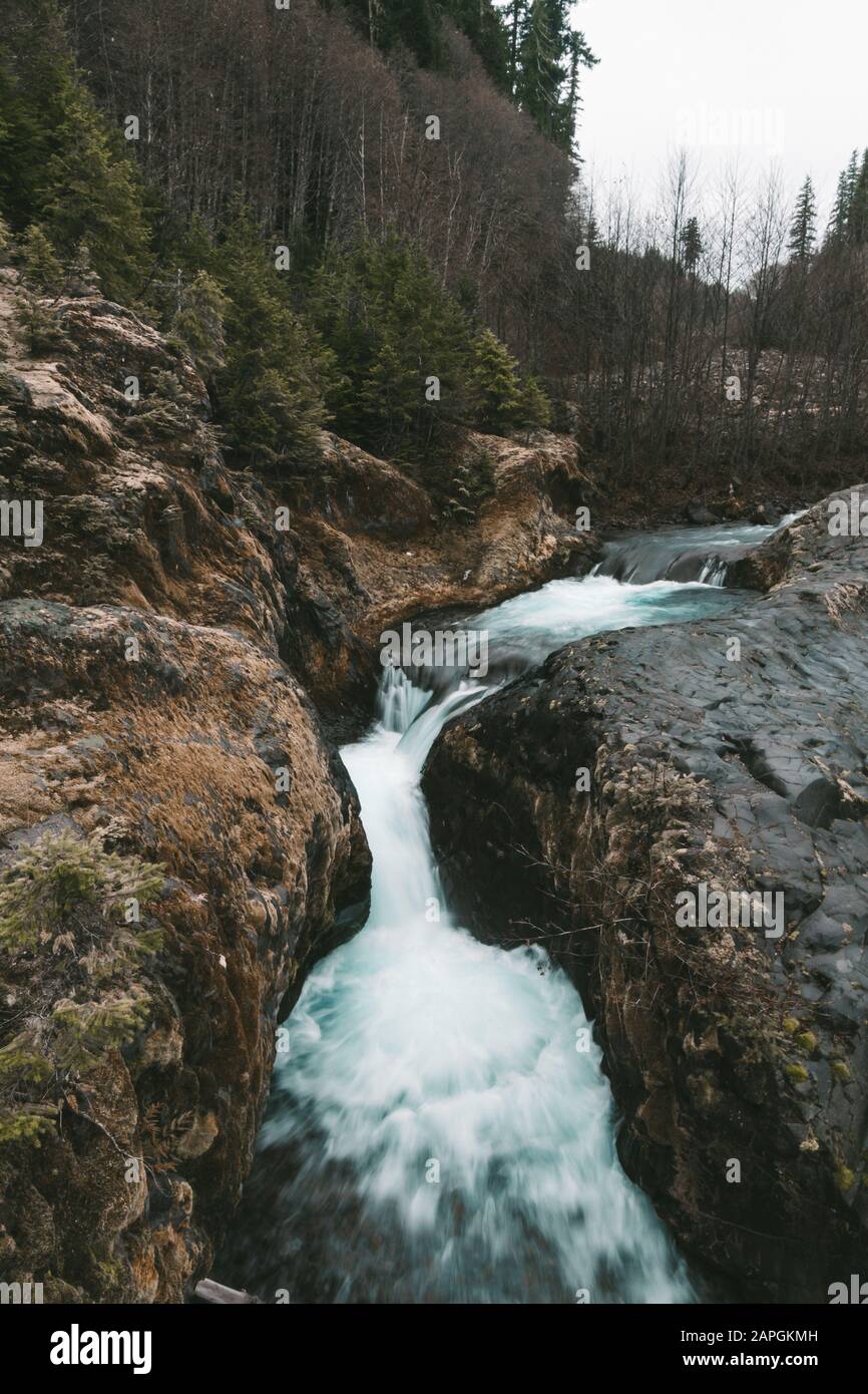 Vertical picture of a river surrounded by rocks covered in greenery ...