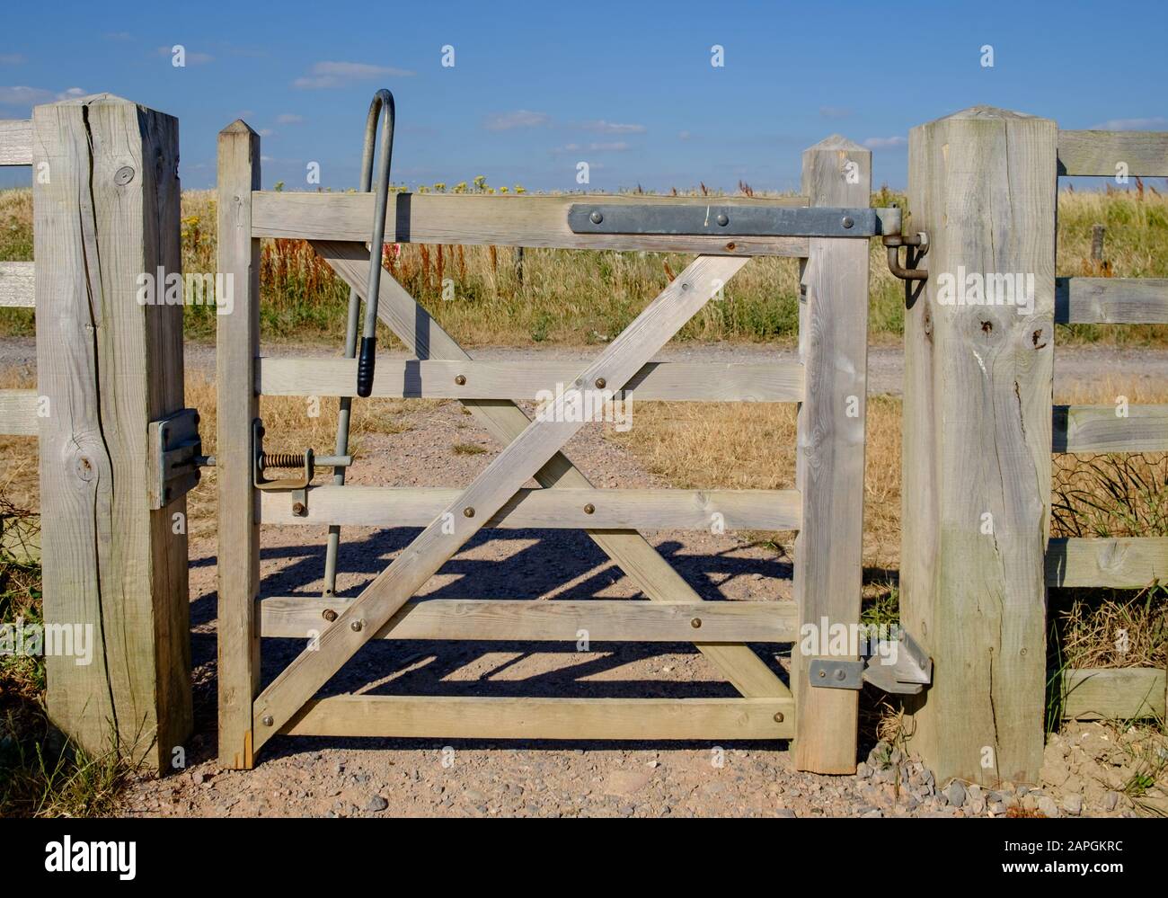 Rugged wooded gate & fence, with footpath & fields in background ...