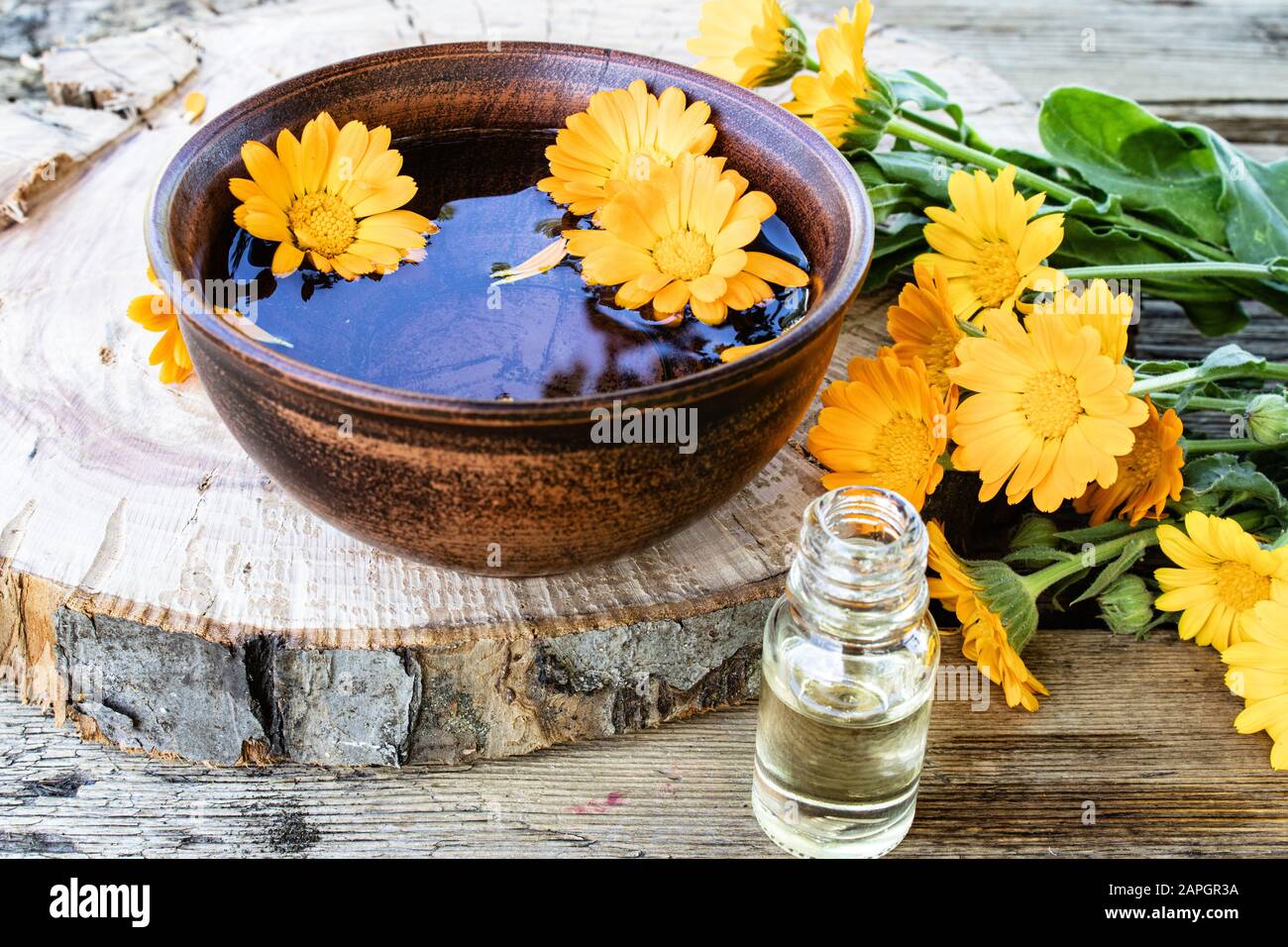 Calendula essential oil near the yellow flowers of calendula on a ...