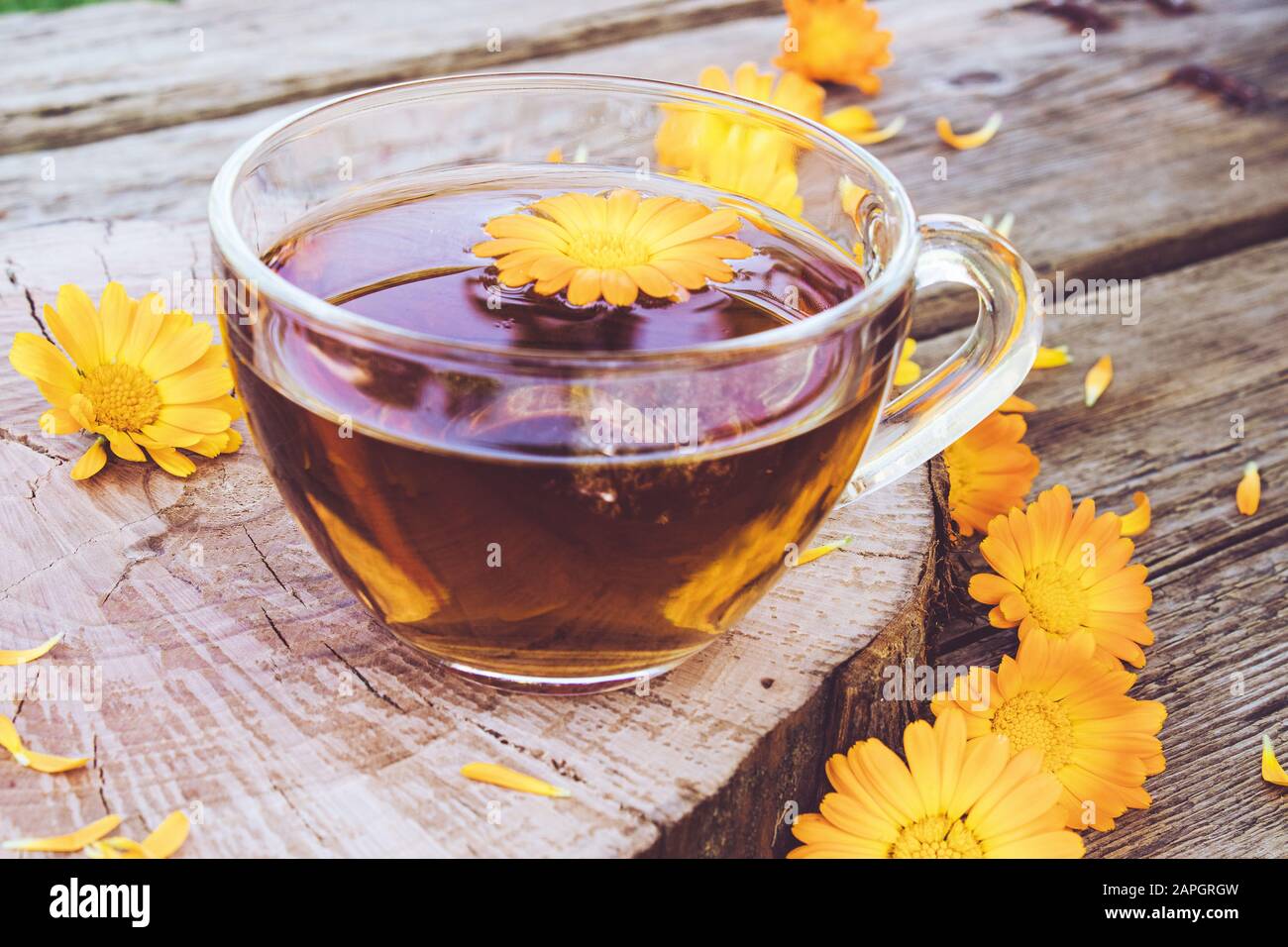 Herbal tea from calendula flowers in a transparent glass mug. Extract ...