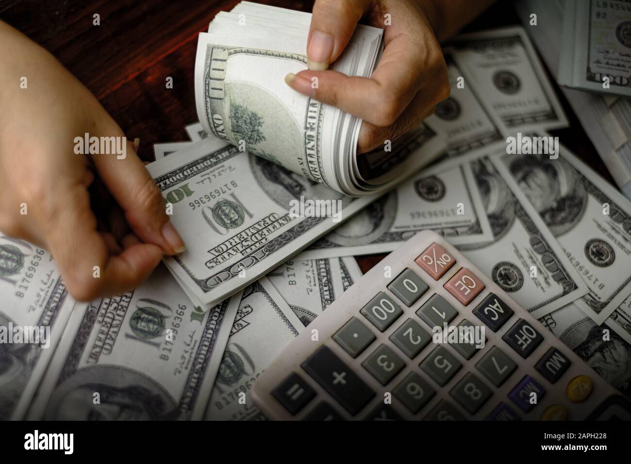 Businessmen women counting money on a stack of 100 US dollars banknotes ...