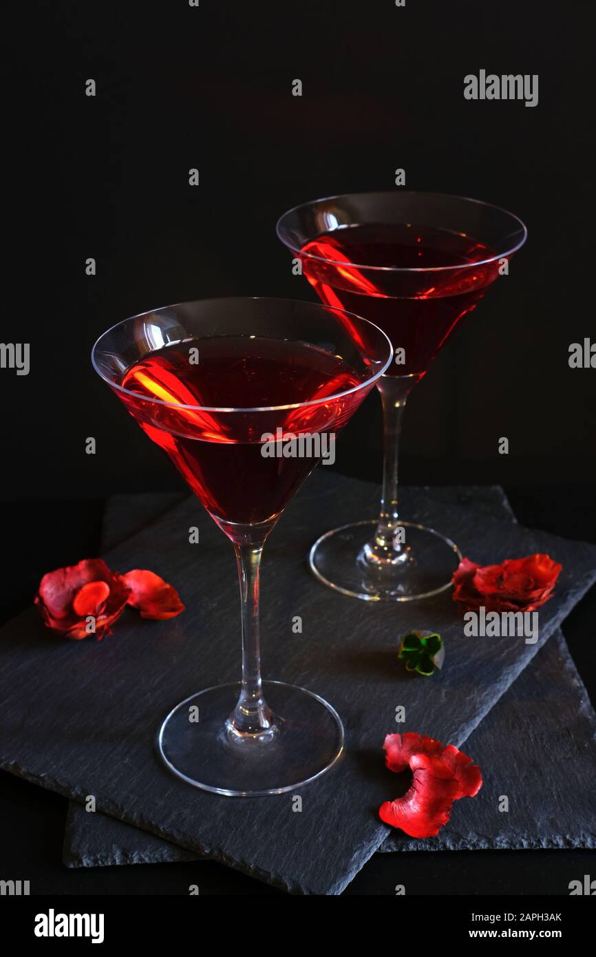 Two cosmopolitan cocktails in a triangular glass. Against a dark ...