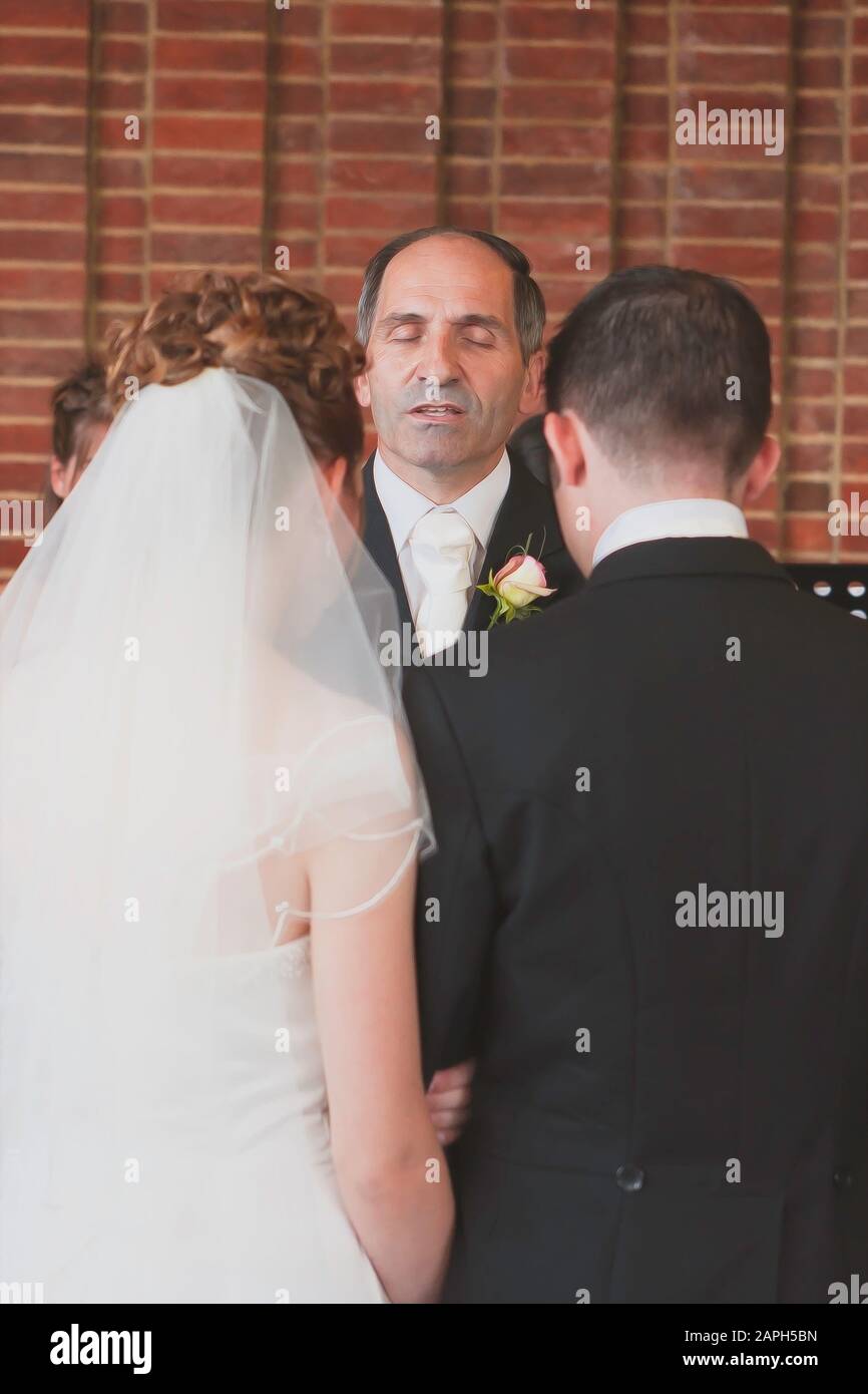 A bride and groom stand in front of a vicar at wedding ceremony Stock ...