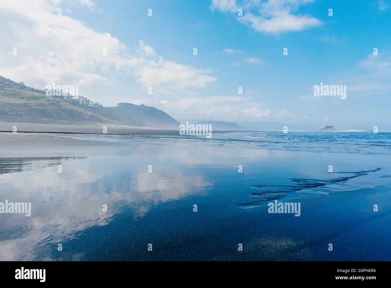 Ocean beach with blue sky reflection on wet sand Stock Photo - Alamy