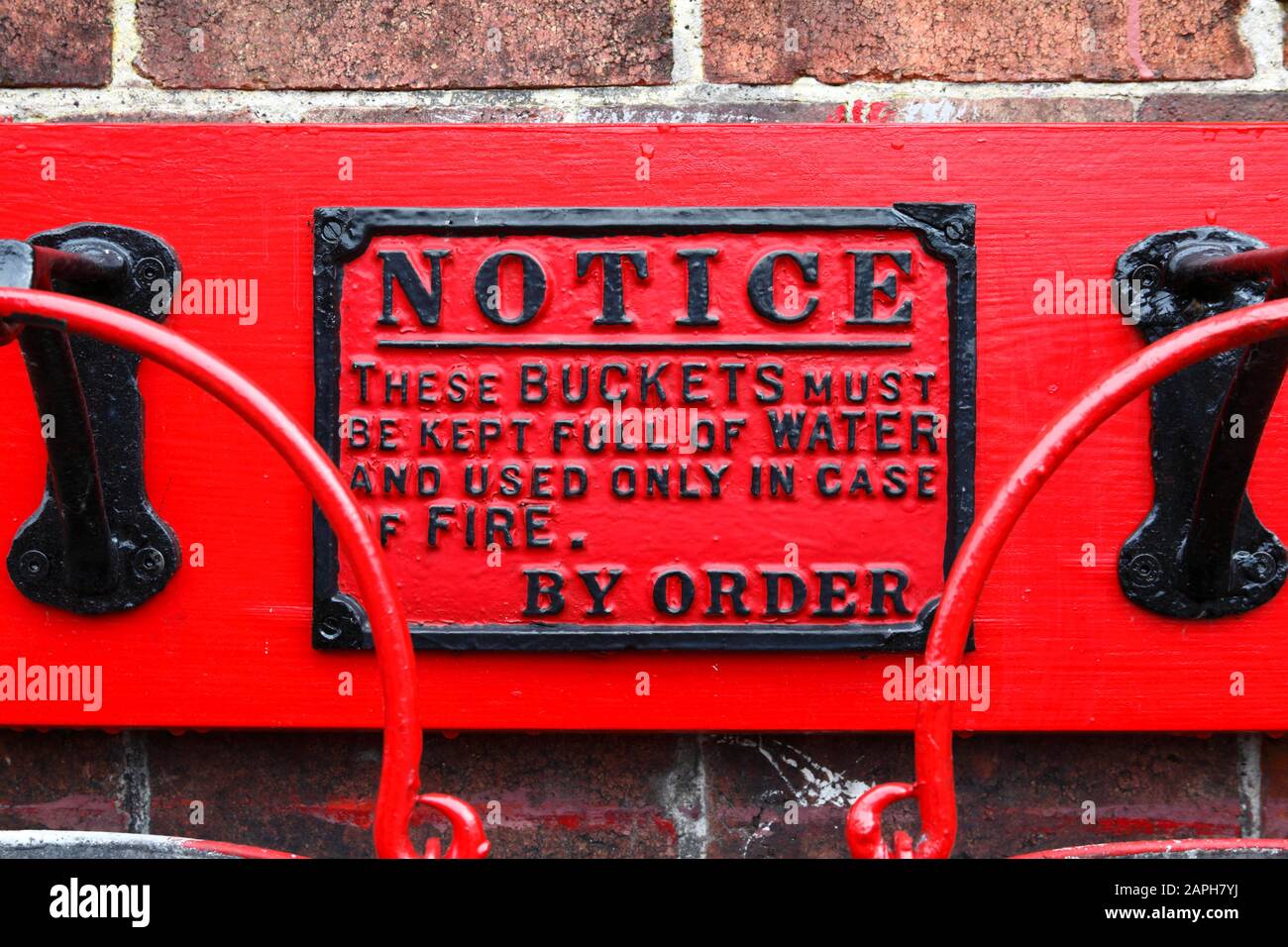 Close up of notice next to fire buckets on station building wall ...
