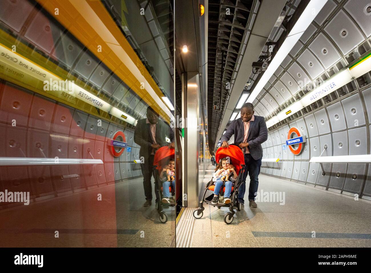 A man boards a Jubilee line train at Westminster with his buggy Stock ...