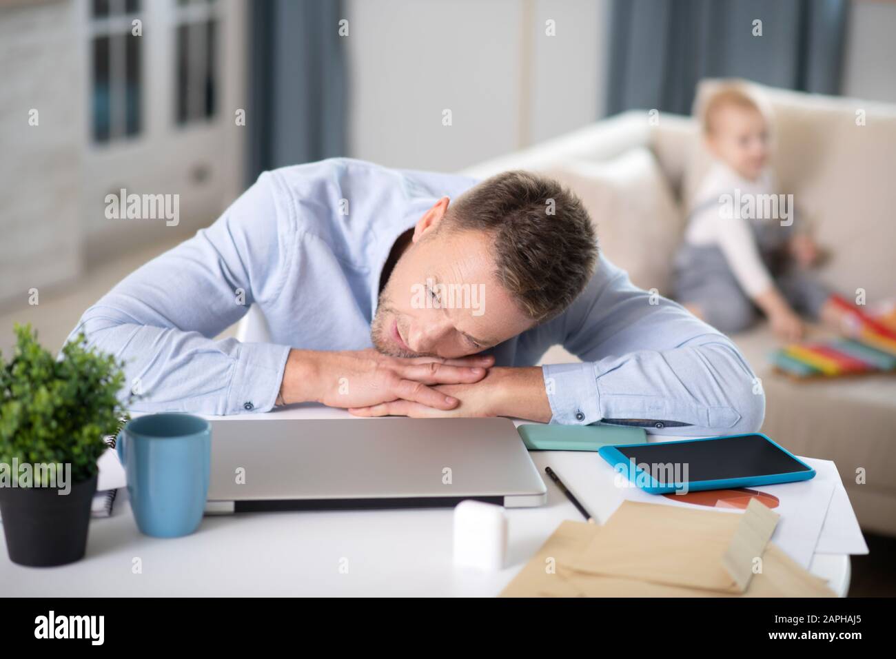 Bearded man in a blue shirt having a nap Stock Photo - Alamy