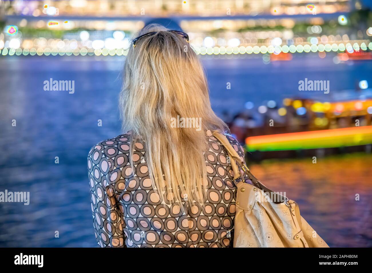Beautiful woman watching city river and skyline at sunset, back view ...