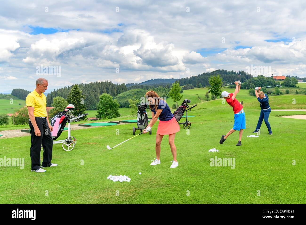 Golf players practising with golf pro on drivingrange Stock Photo - Alamy