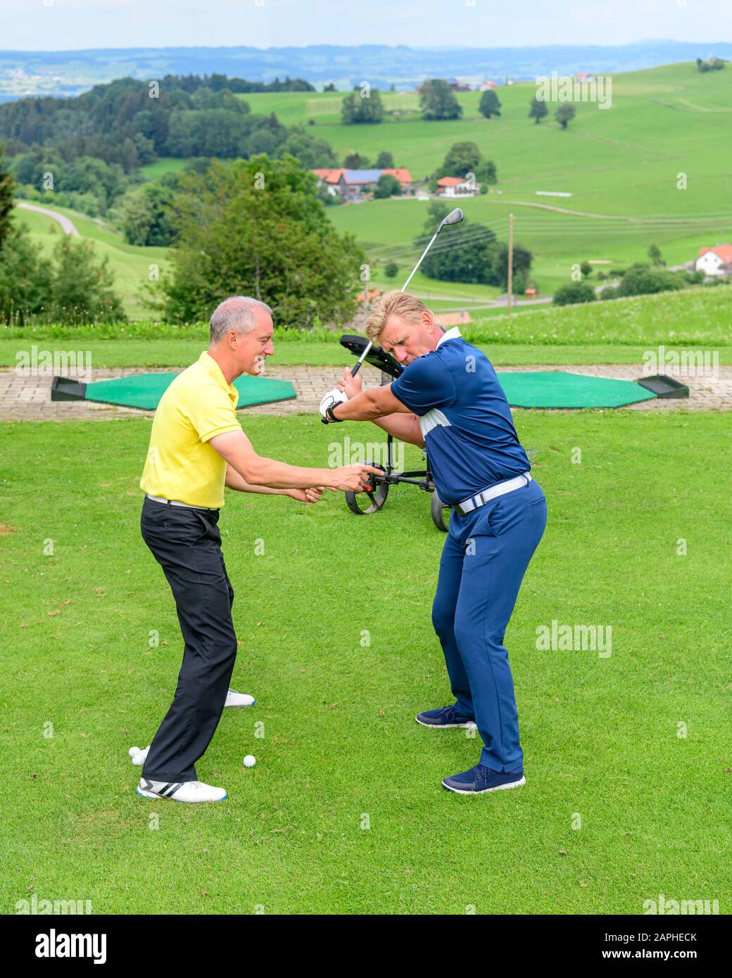 Golf players practising with golf pro on drivingrange Stock Photo - Alamy