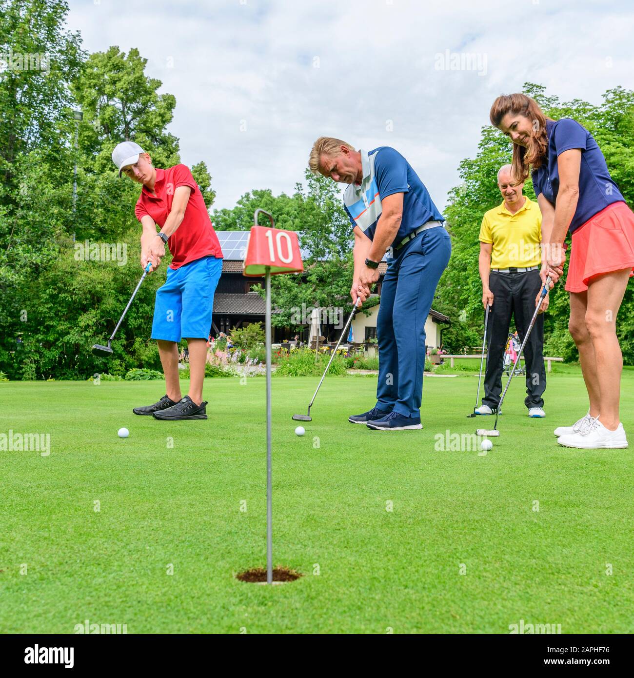 Golf players practising with golf pro on putting green Stock Photo - Alamy