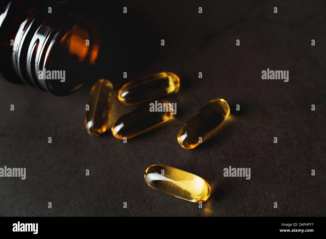 Macro photo of Omega 3 capsules and a derk glass jar on a black ...