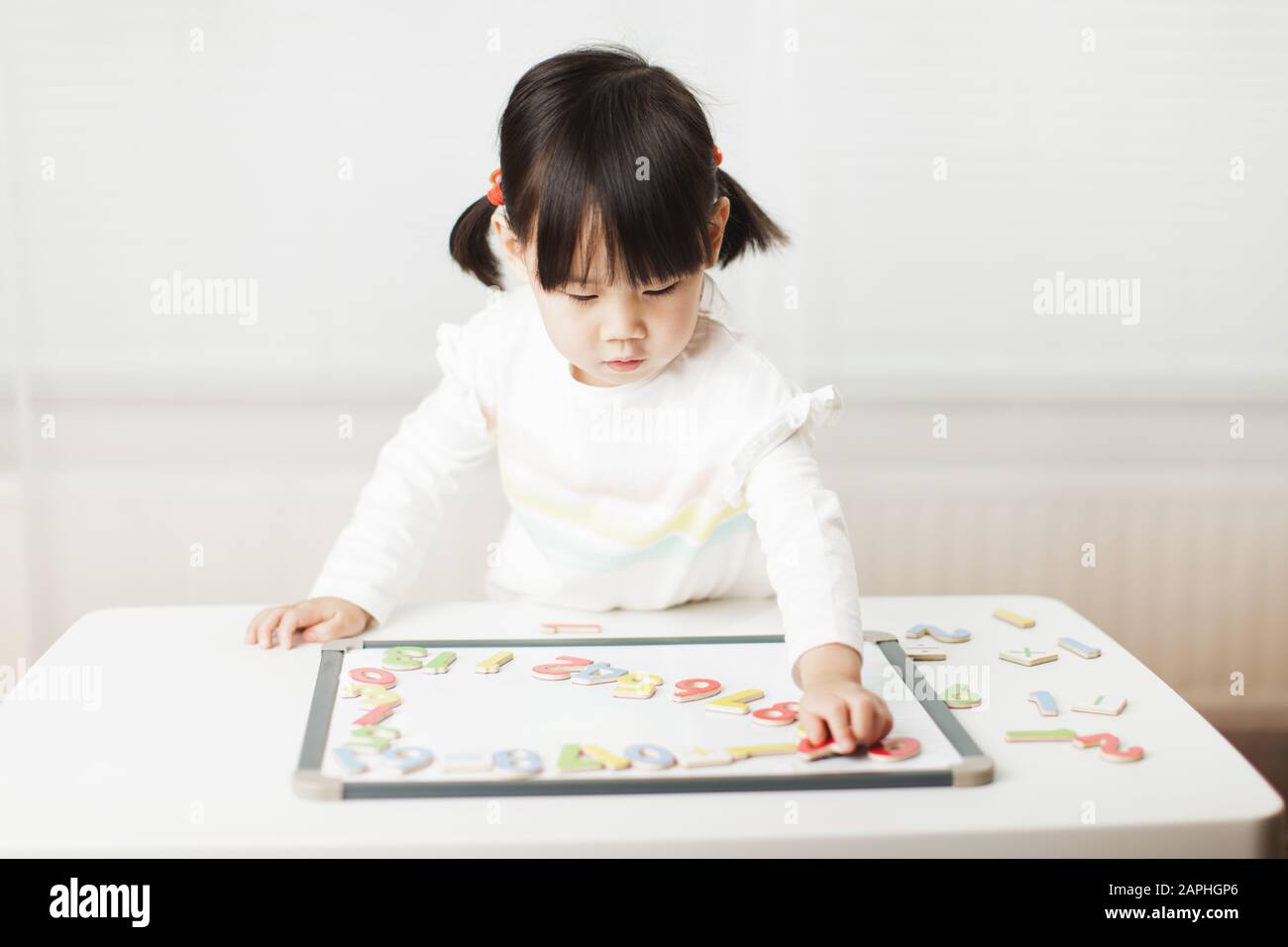 toddler girl learning math on white board against white background ...