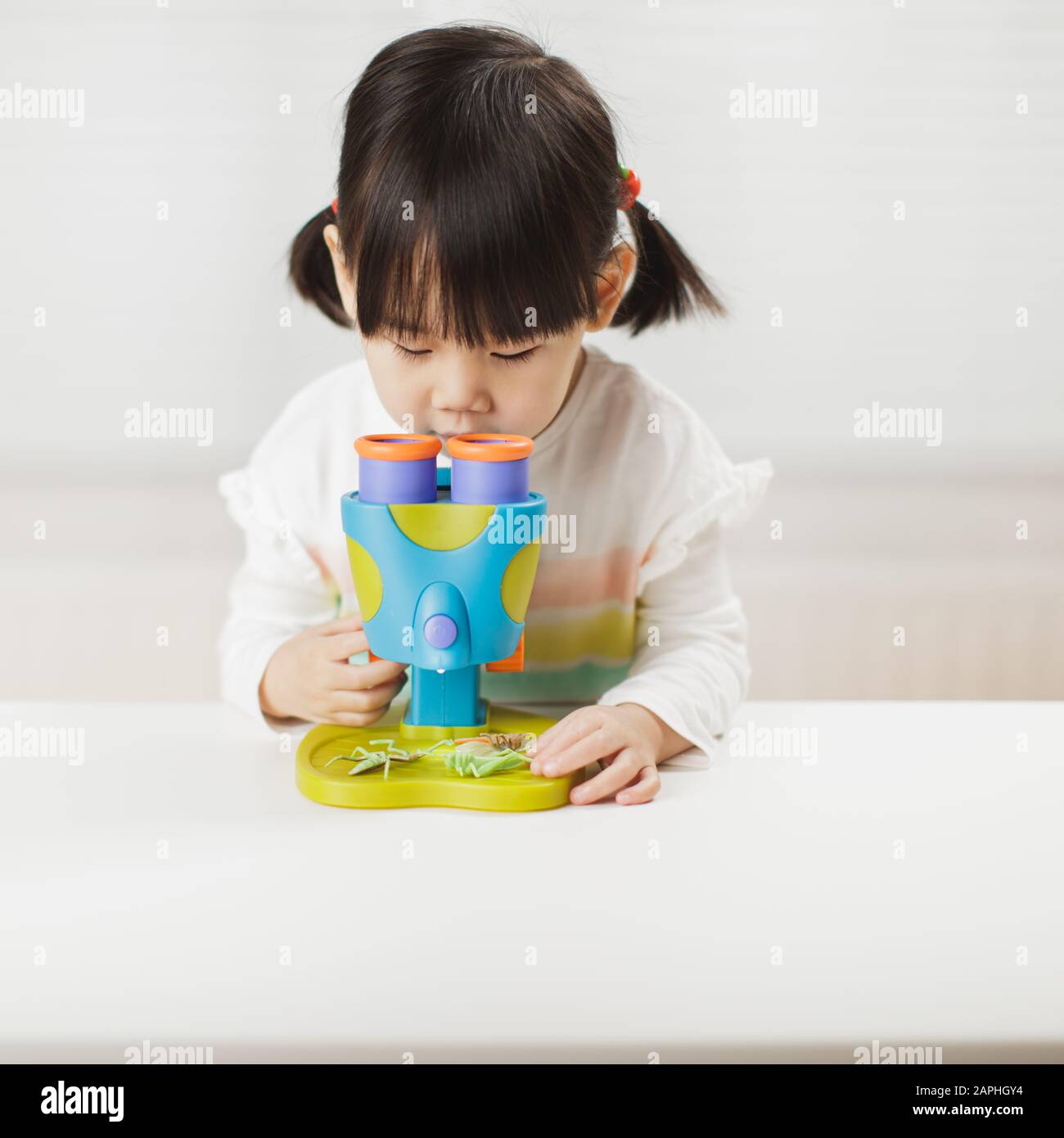 toddler girl pretend play scientist role using microscope at home ...