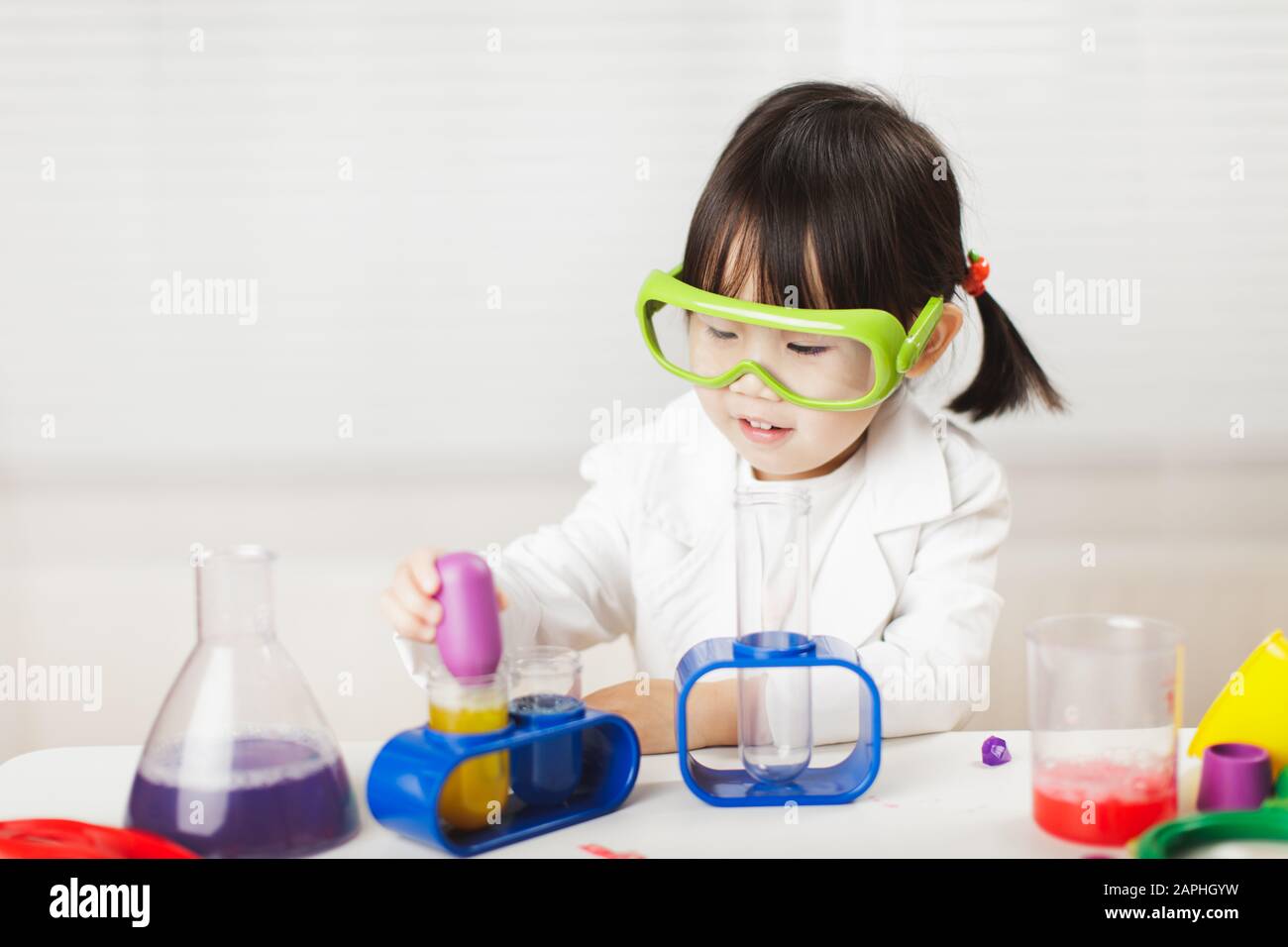toddler girl pretend play scientist role at home against white ...