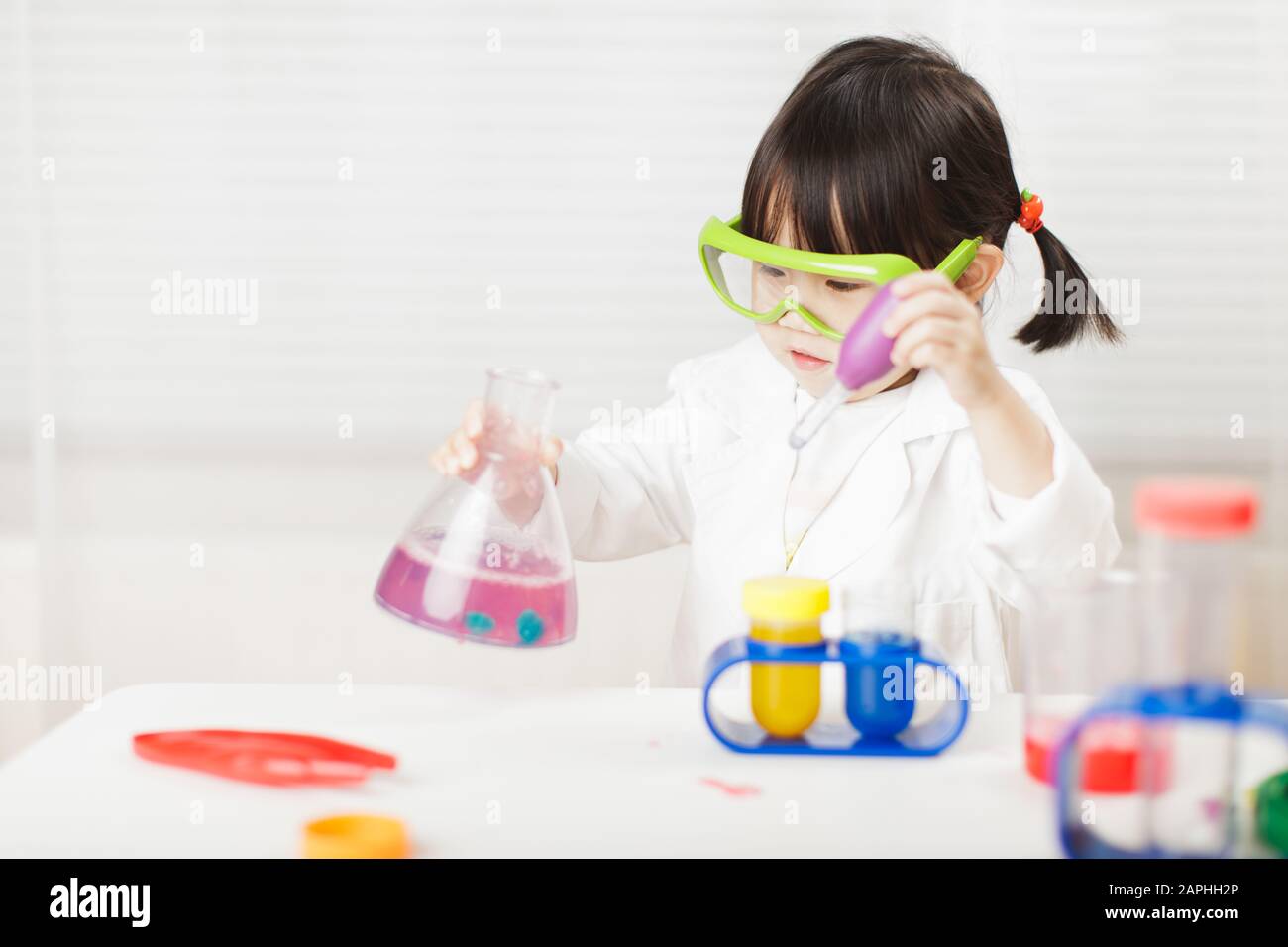 toddler girl pretend play scientist role at home against white ...