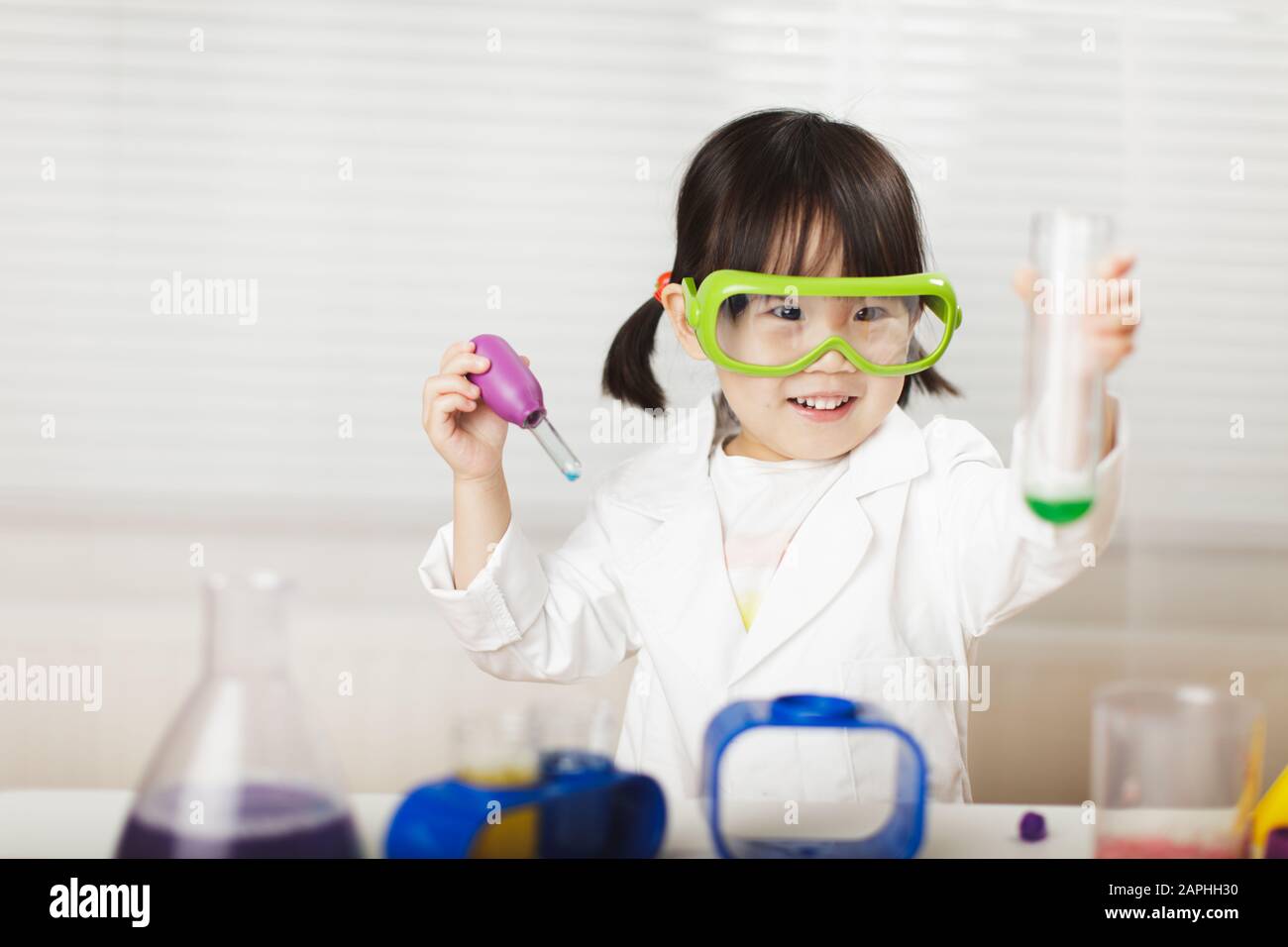 toddler girl pretend play scientist role at home against white ...