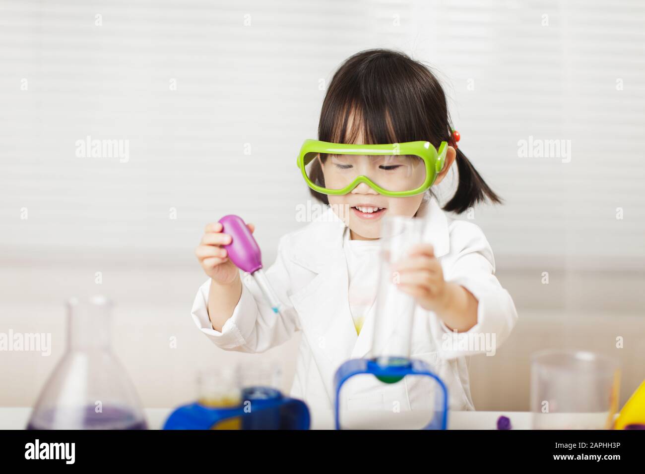 toddler girl pretend play scientist role at home against white ...