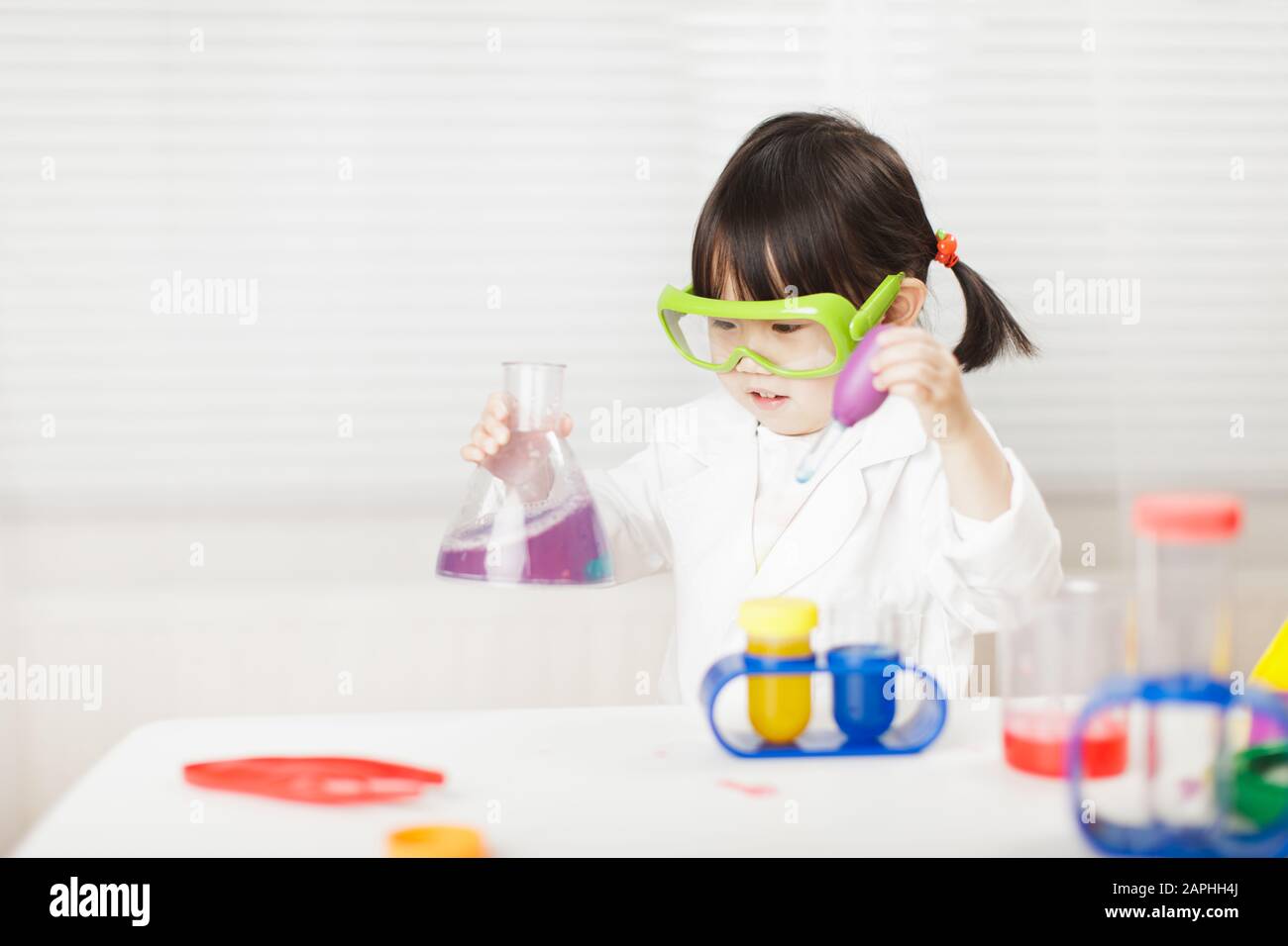 toddler girl pretend play scientist role at home against white ...