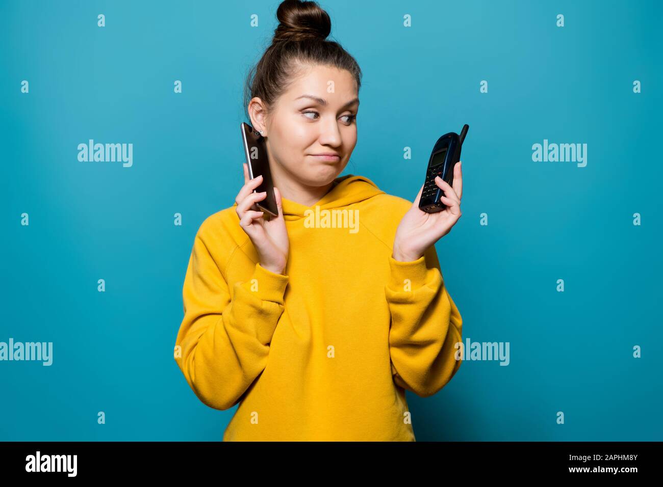 young woman puts a smartphone to her ear and looks at the old push ...