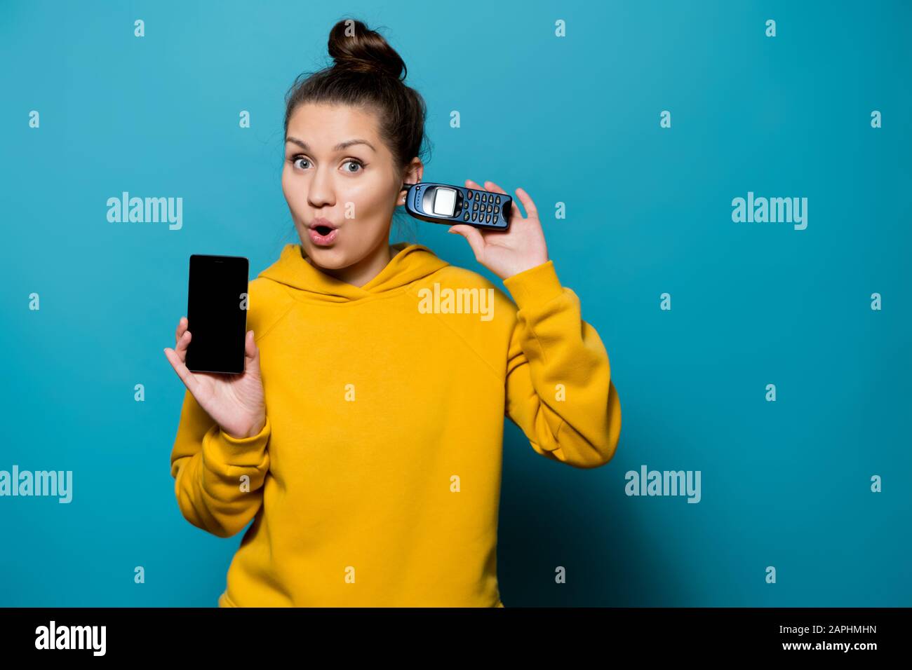 a girl shows a smartphone, and with her other hand holds an old cell ...