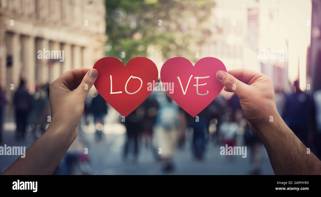 Two hands holding different paper heart symbols, unite them to create ...