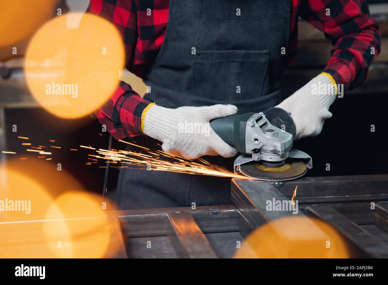 Worker hand with electric wheel grinding on steel structure in factory ...