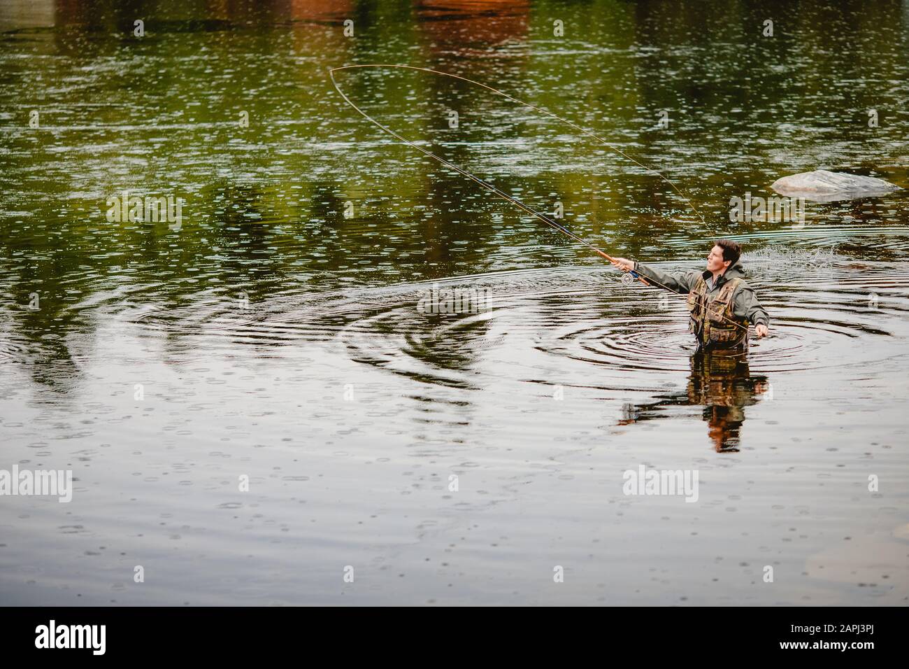 Fisherman using rod fly fishing in river morning standing in water ...
