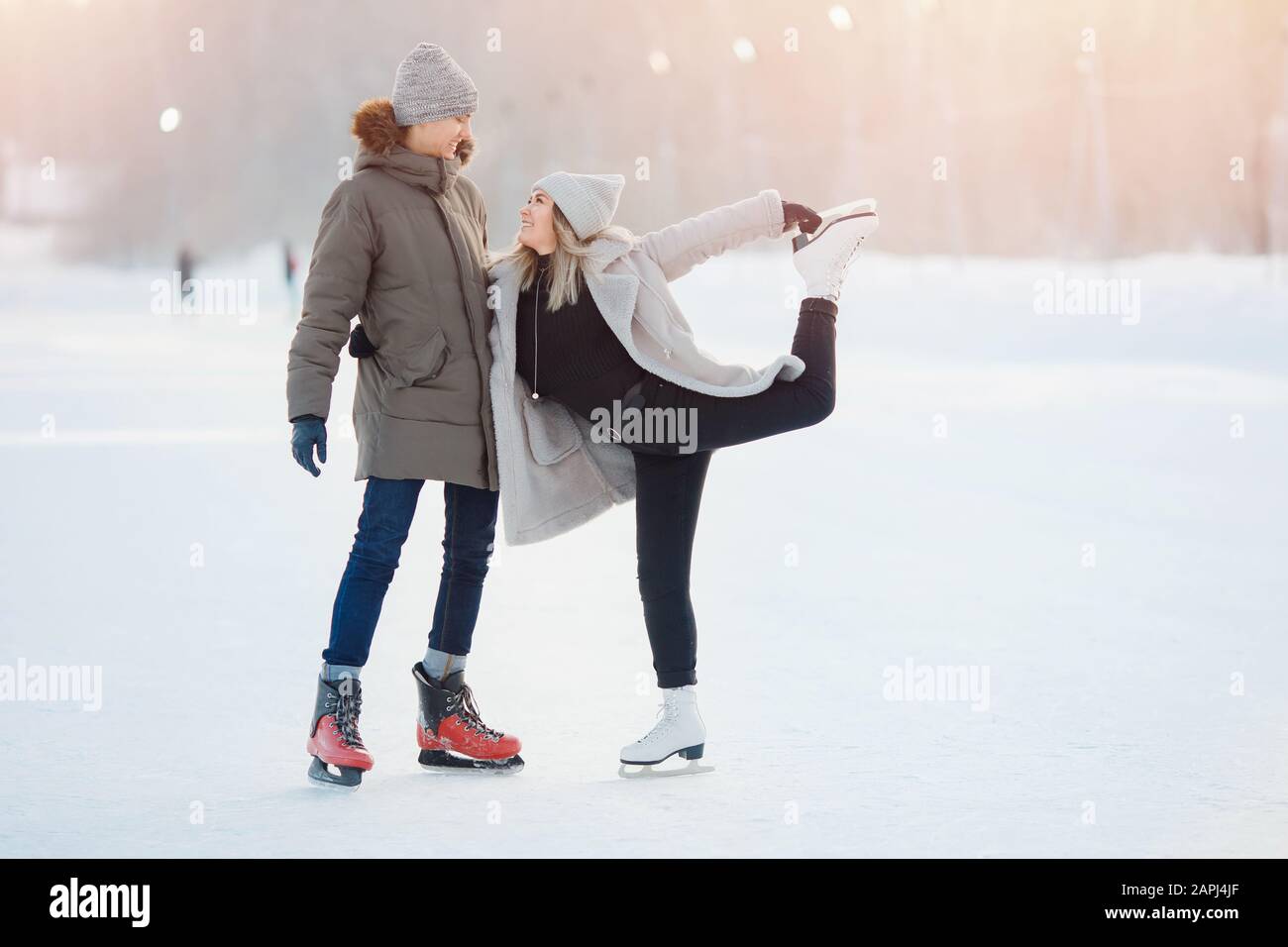 Winter skates, loving couple holding hands and rolling on rink. Concept ...