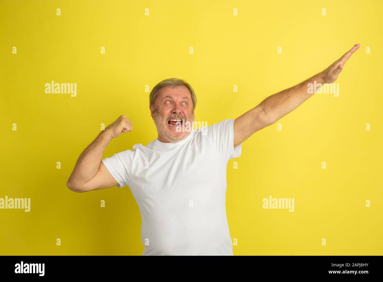 Successful winner's gesture. Caucasian man portrait isolated on yellow ...
