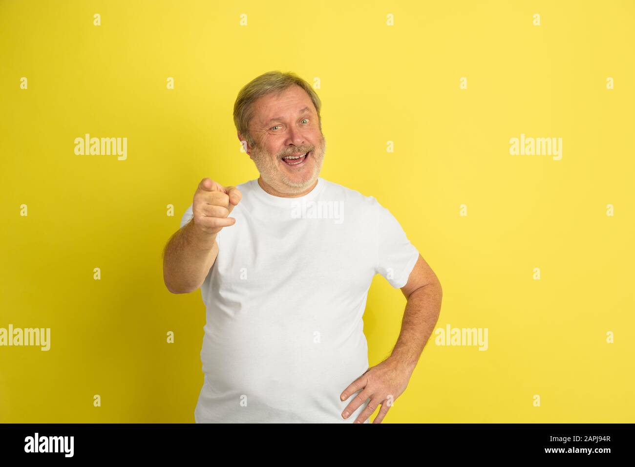 Pointing, choosing you. Caucasian man portrait isolated on yellow ...