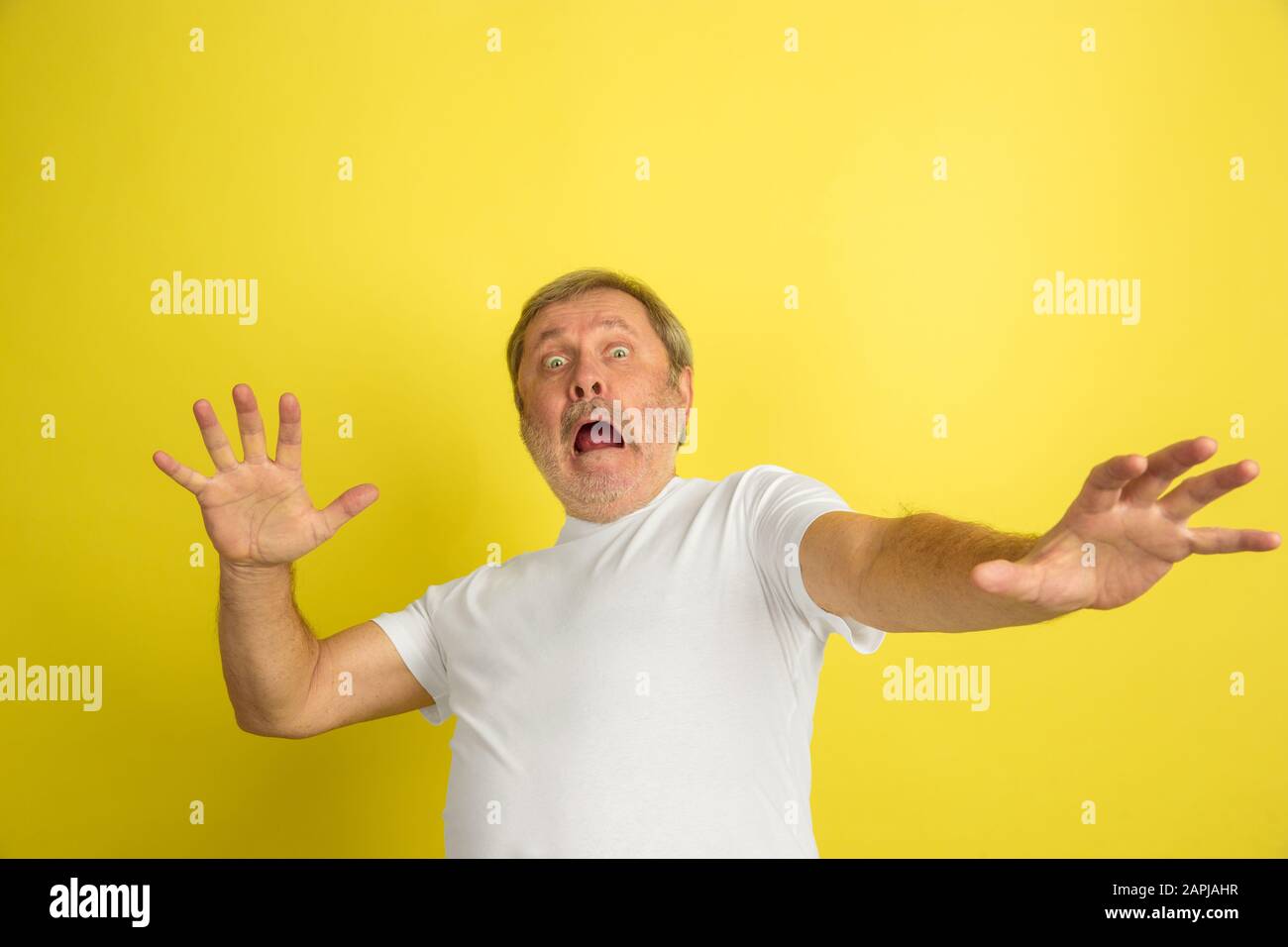 Scared, shocked. Caucasian man portrait isolated on yellow studio ...