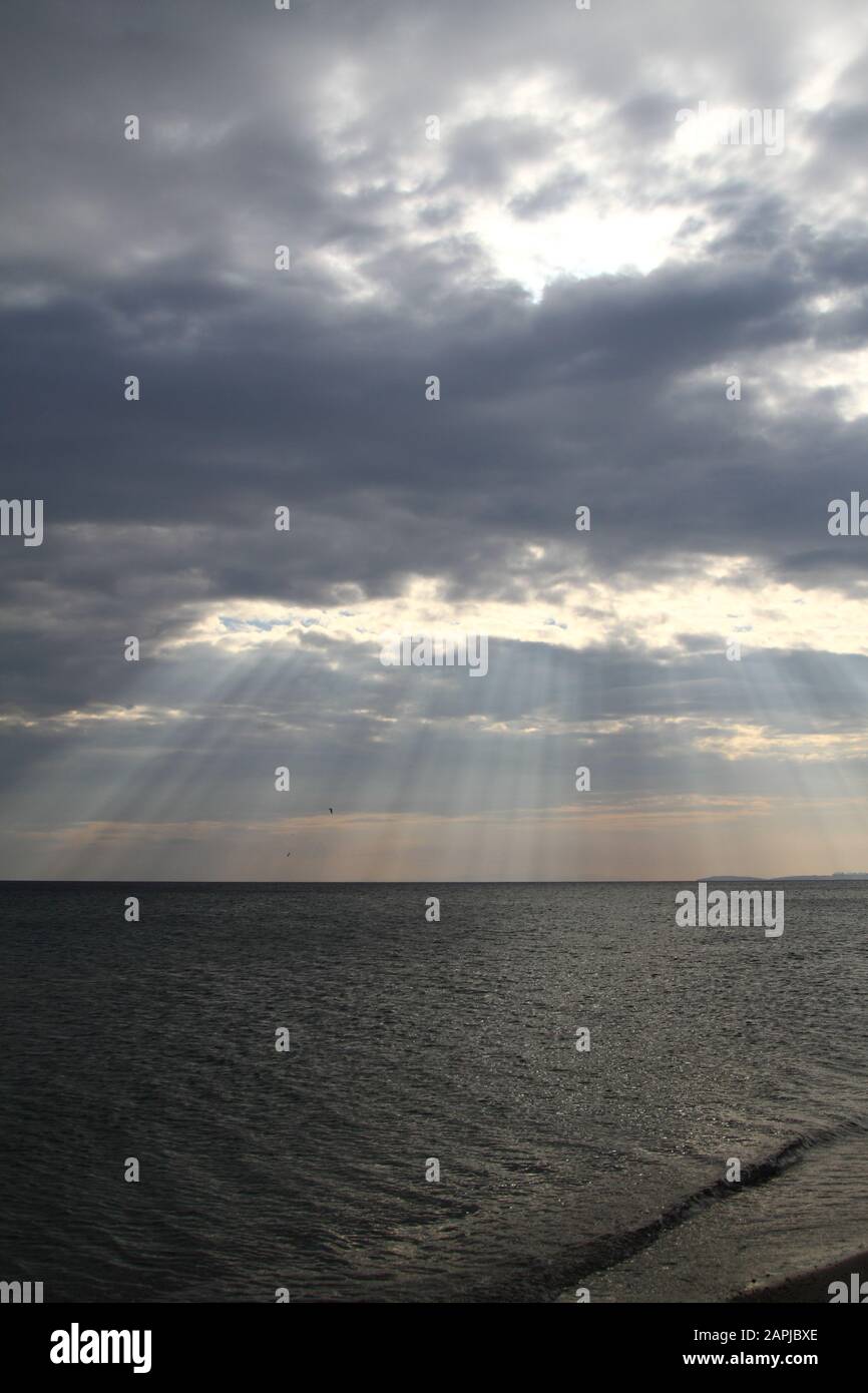 Sun rays beaming through picturesque clouds above the sea. Sun, clouds ...