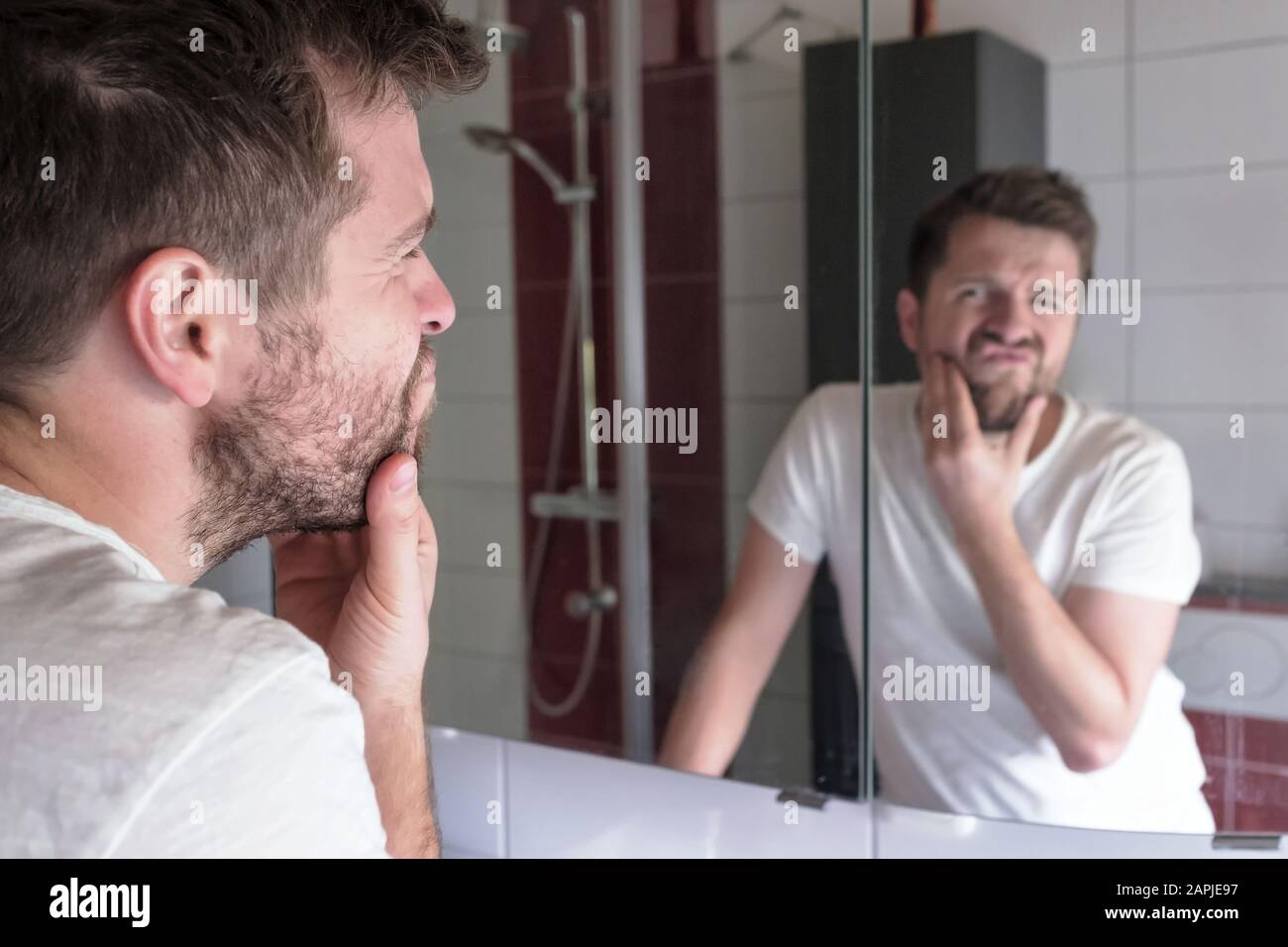 Man check condition of his skin in mirror reflection at the bathroom ...
