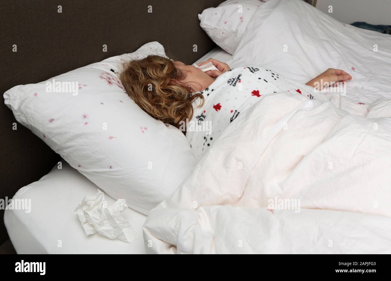 A woman is lying in bed with flu during a flu epidemic Stock Photo - Alamy