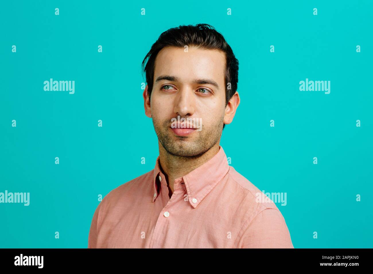Portrait of a young adult man serious, looking left, isolated on blue ...