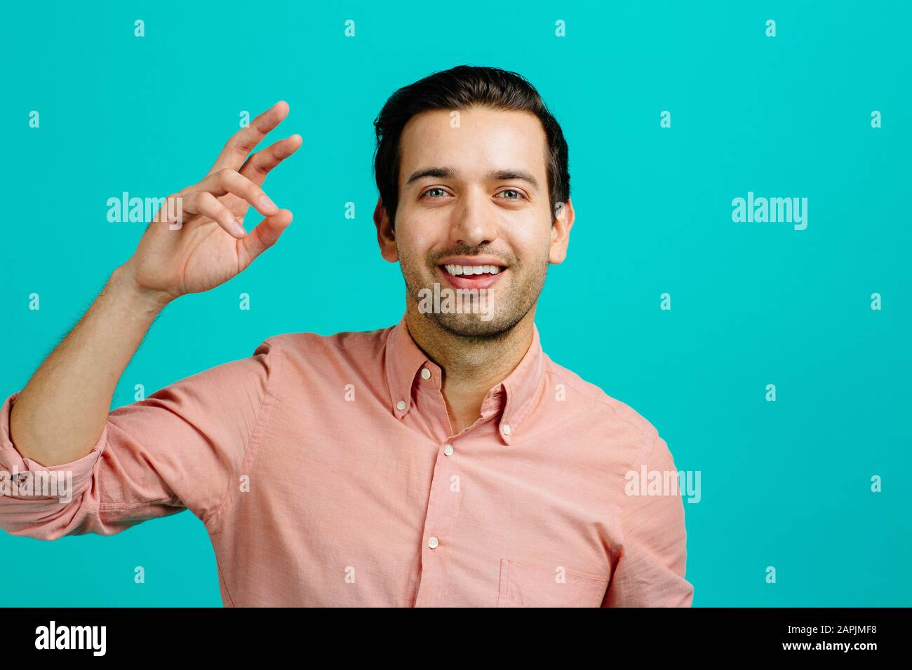 Portrait of a young adult man smiling, isolated on blue studio ...