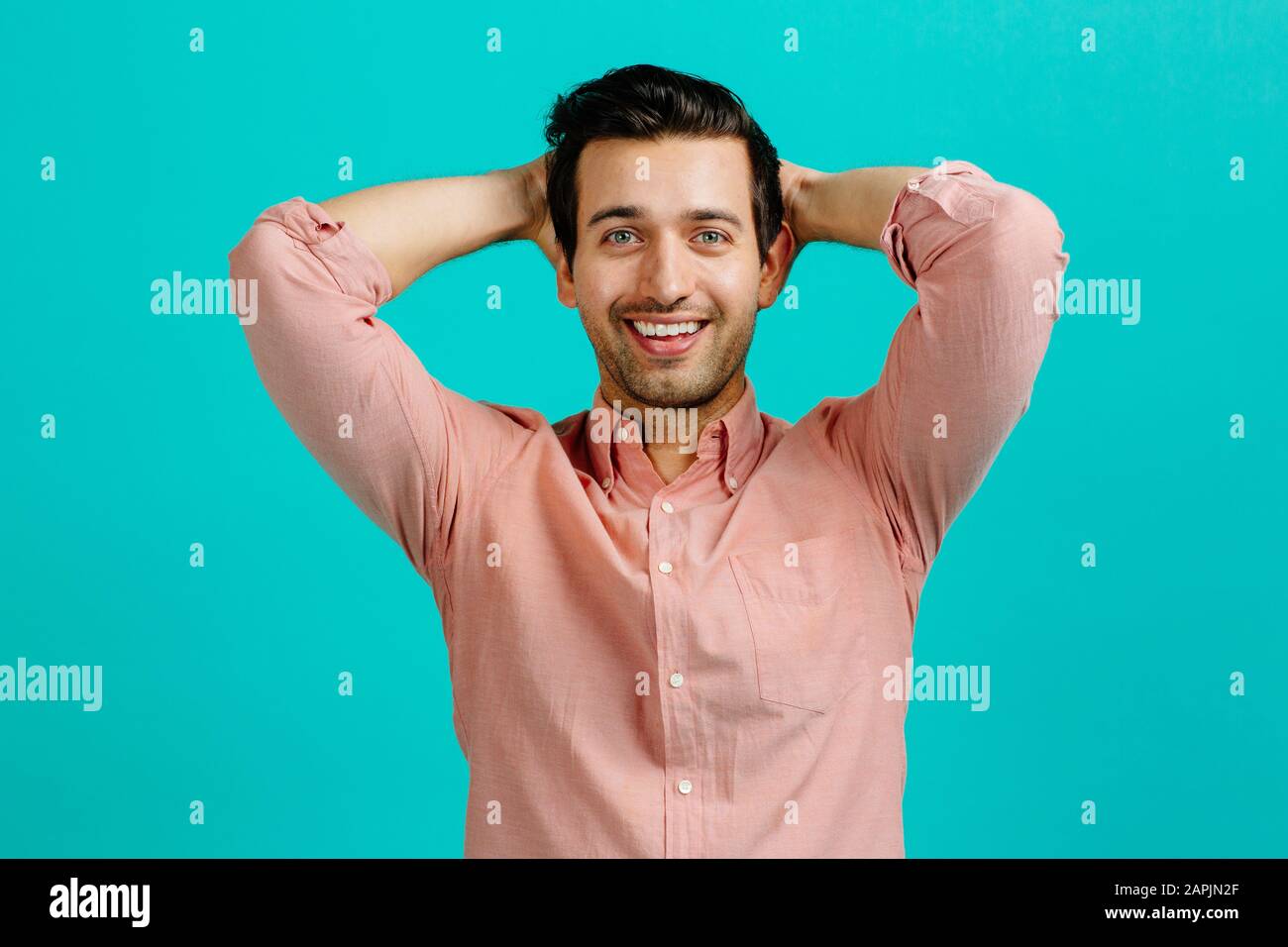 Portrait of a young adult man smiling, isolated on blue studio ...